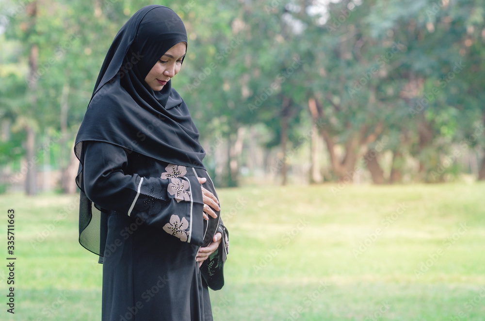 Muslims pregnant touching her womb in green garden, felt love for the ...
