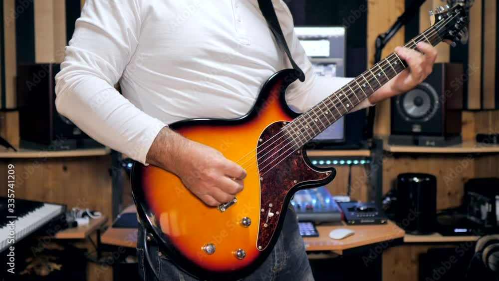 Static medium shot of a guitarist playing his electric guitar in a home ...
