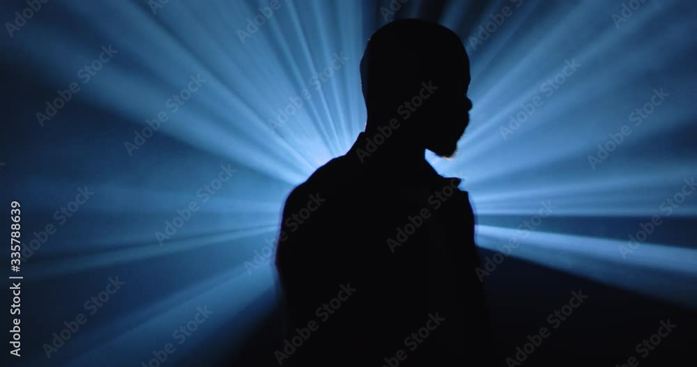 Dark black silhouette of man posing and dancing in darkness space in ...