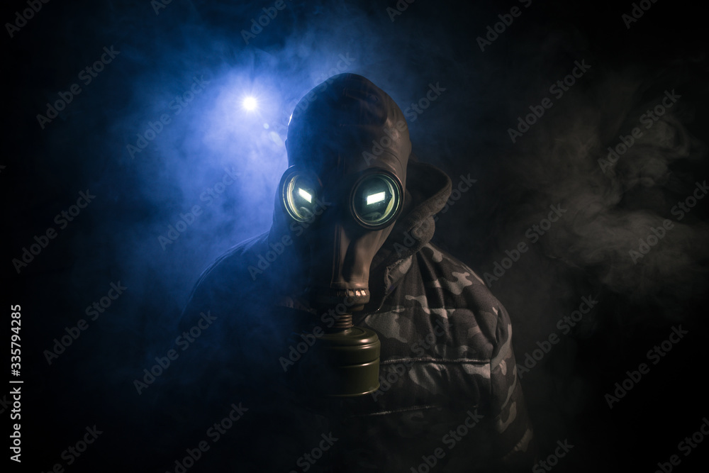 Gas mask with clouds of smoke on a dark background. Sign of radioactive ...