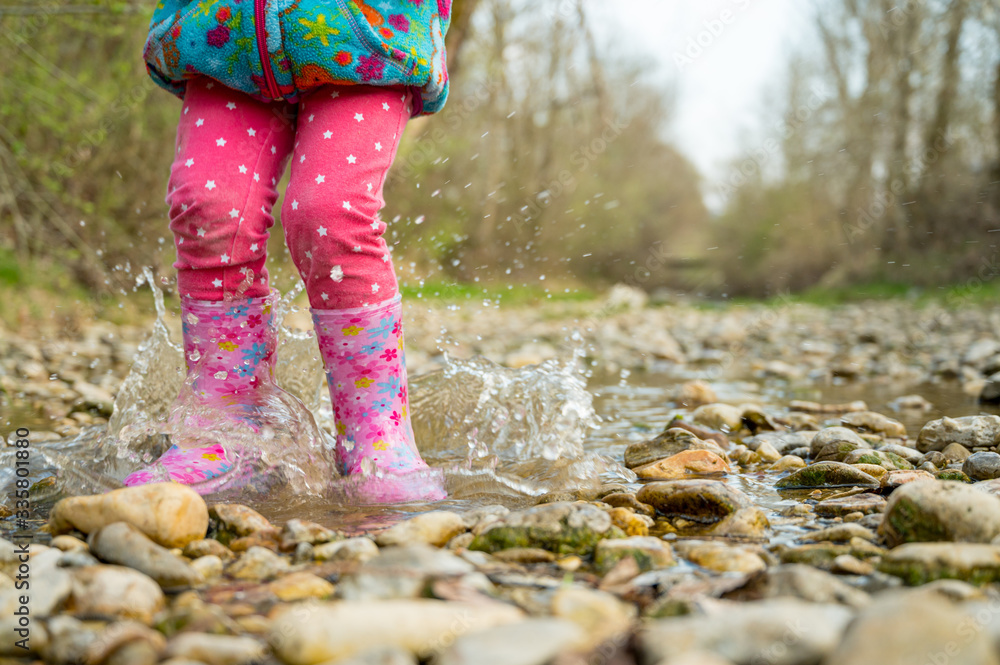 Young girl walking along a shallow stream with rubber pink boots. Stock ...
