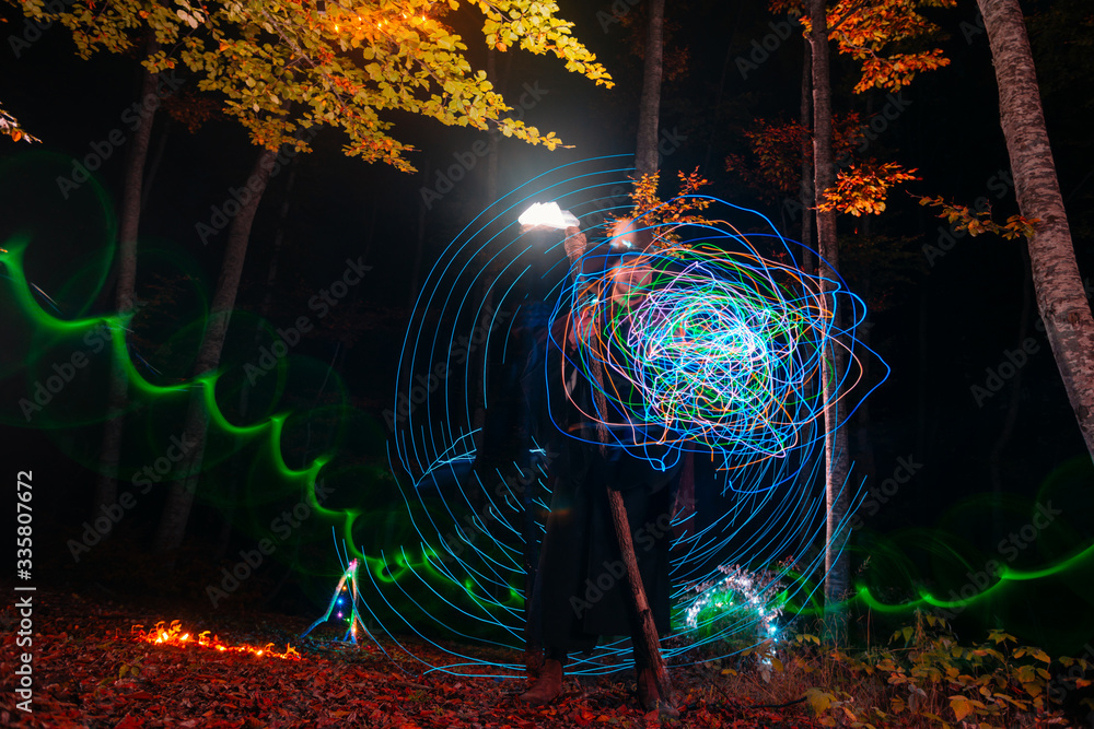Sorcerer (magician) casting a spell while standing in the magical woods ...