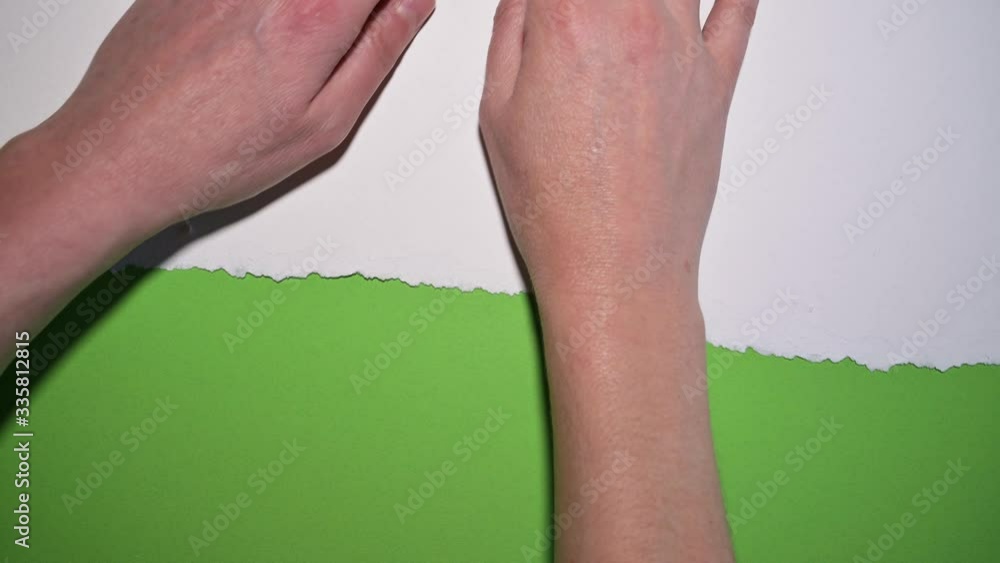 Hands tearing white paper horizontal revealing a green screen Stock ...