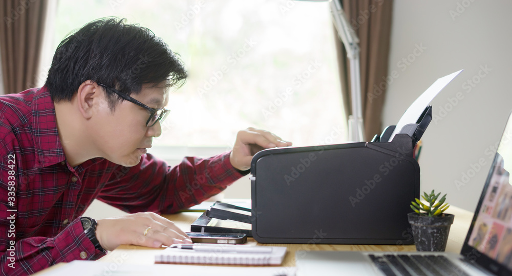 Business owner Asian man using printer for business at study table in ...