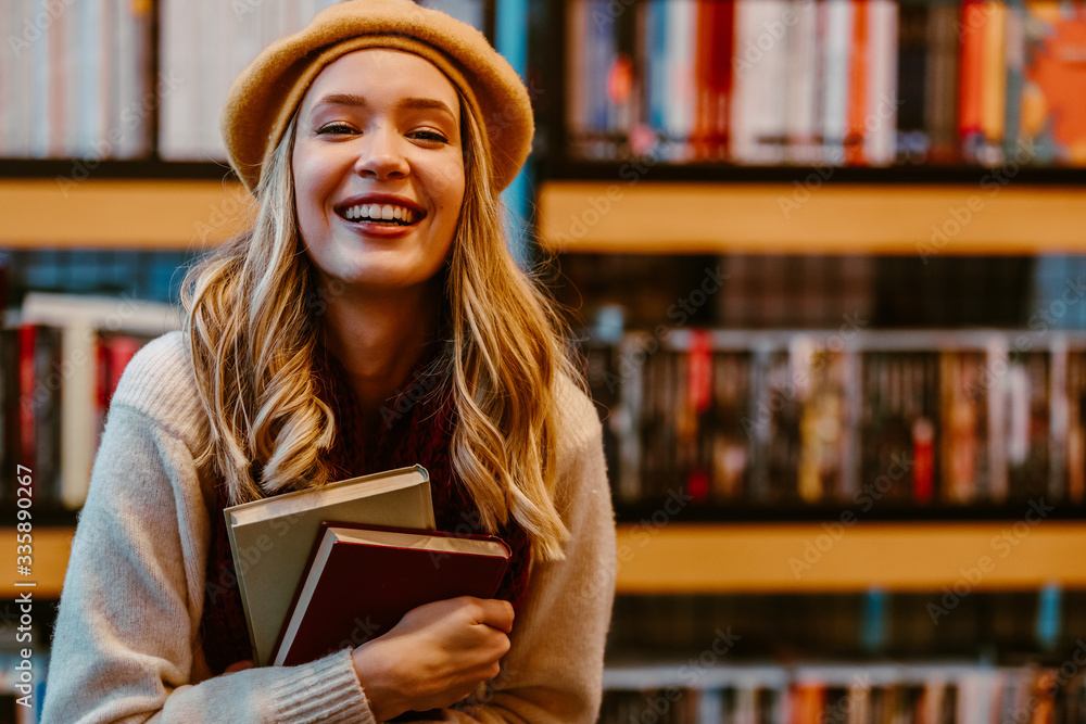 Close photo of beautiful smiling girl visiting bookstore. Girl is ...