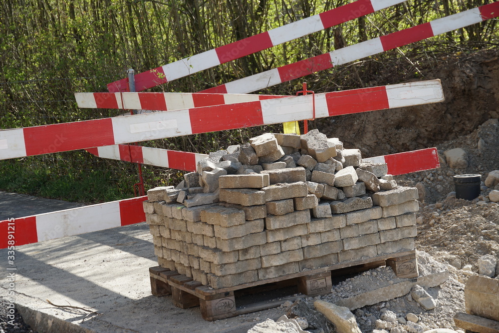 building site of a new sidewalk with a pile of concrete tiles, secured ...