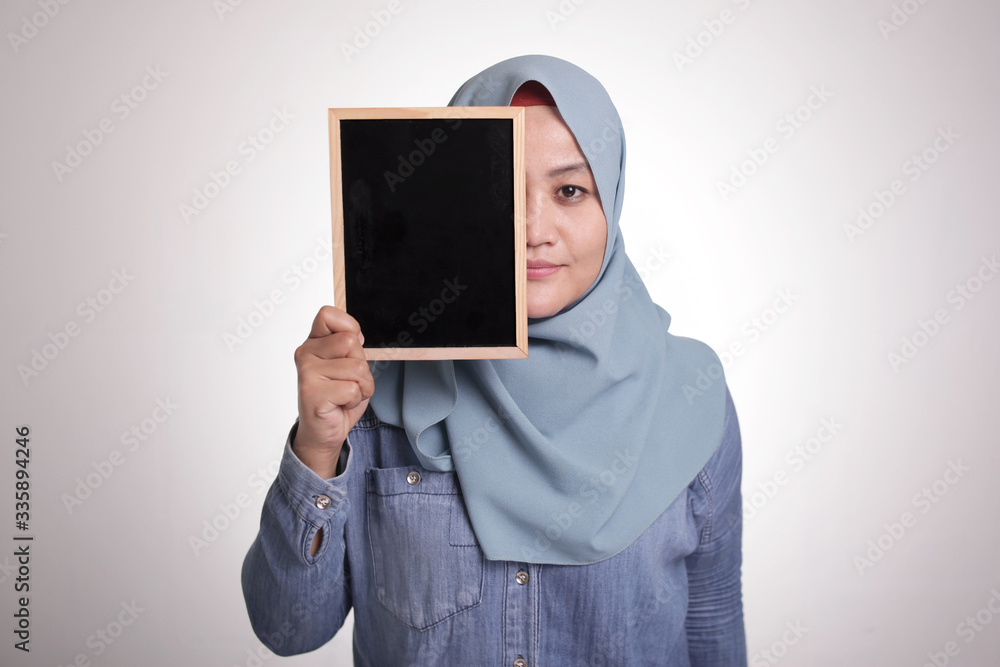 Muslim woman wearing hijab covering her face with blackboard ...