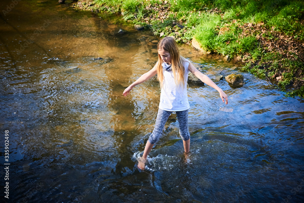 Child cute blond girl playing in the creek. Girl walking barefoot in ...