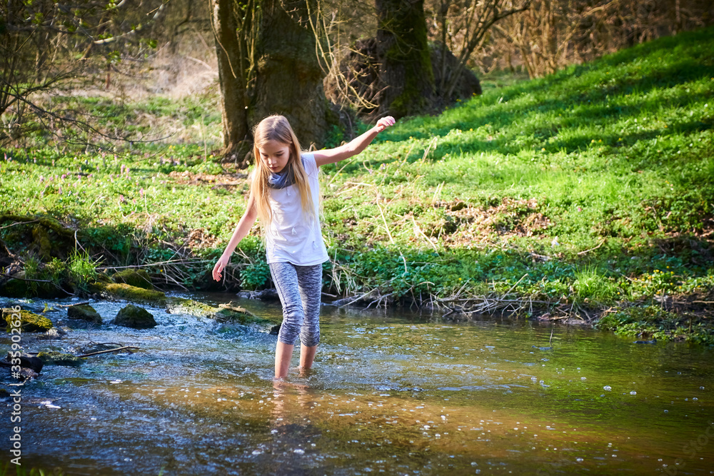 Child cute blond girl playing in the creek. Girl walking barefoot in ...