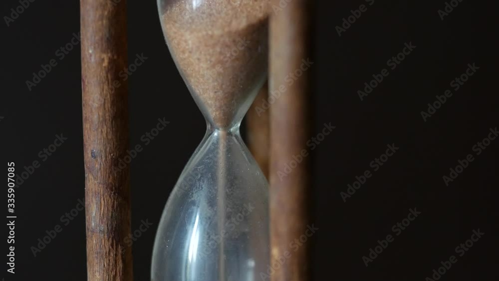 Hypnotic macro one minute running vintage hourglass on dark background ...
