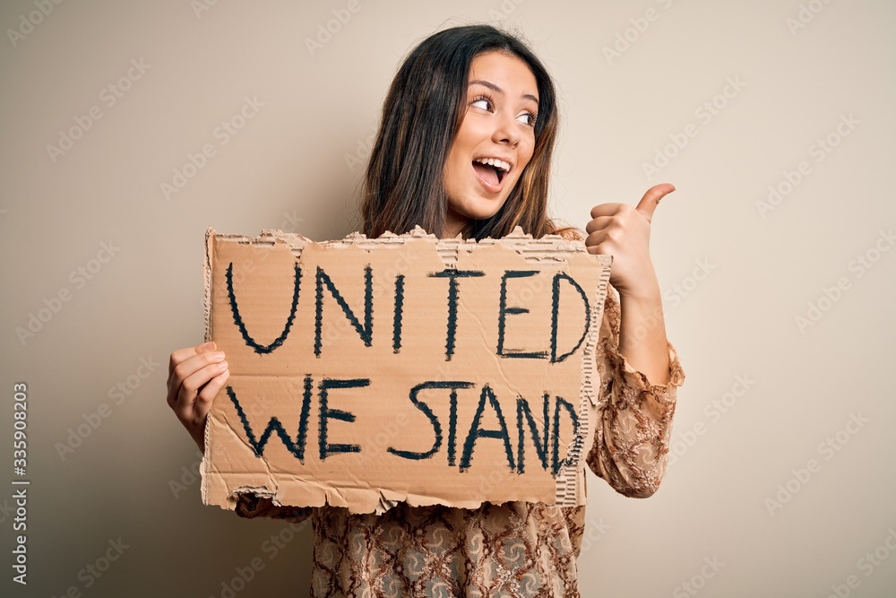 Young beautiful brunette woman asking for union holding banner with ...