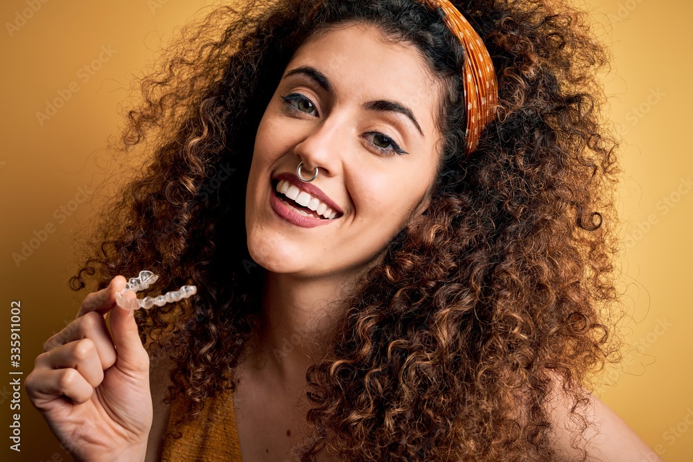 Young beautiful woman with curly hair and piercing holding dental ...