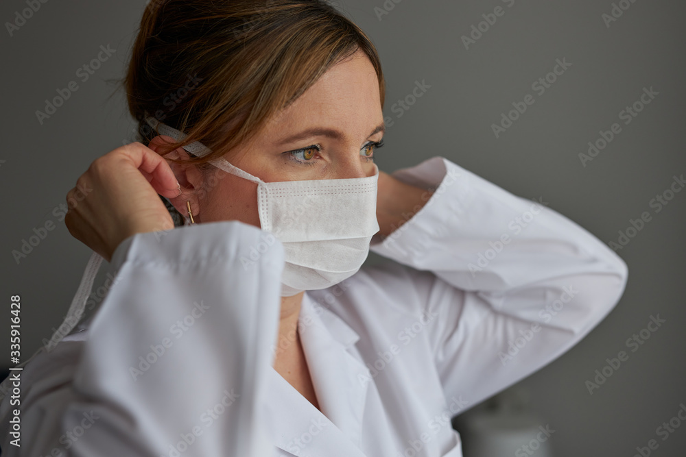 Doctor covering her face with mask. Portrait of young woman wearing the ...