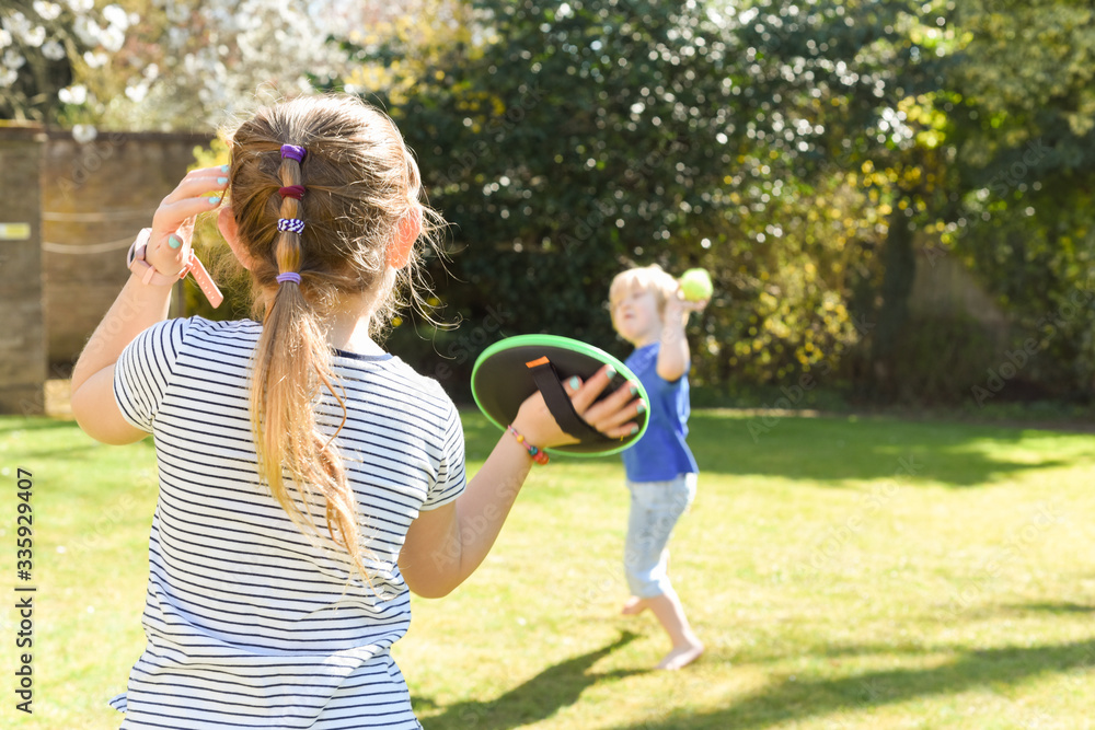 Foto de Children playing outside a brother and sister play a ball game ...