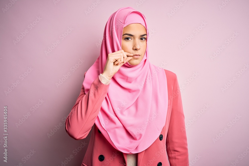 Young beautiful girl wearing muslim hijab standing over isolated pink ...