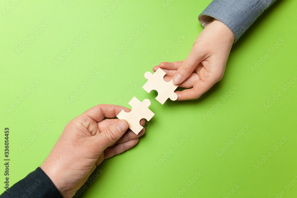 Two hands connect puzzles on a green background. Cooperation and ...