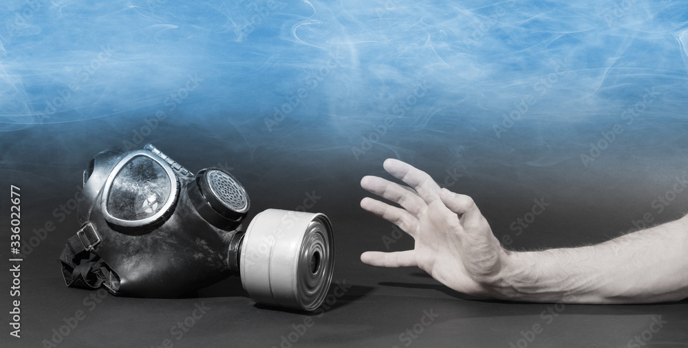 Man in room filled with smoke, trying to reach for vintage gasmask ...