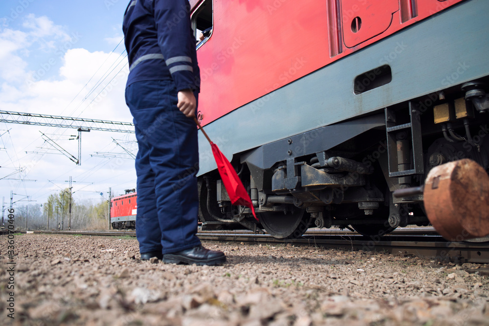 Railroad worker or switchman with red flag standing by the train at the ...