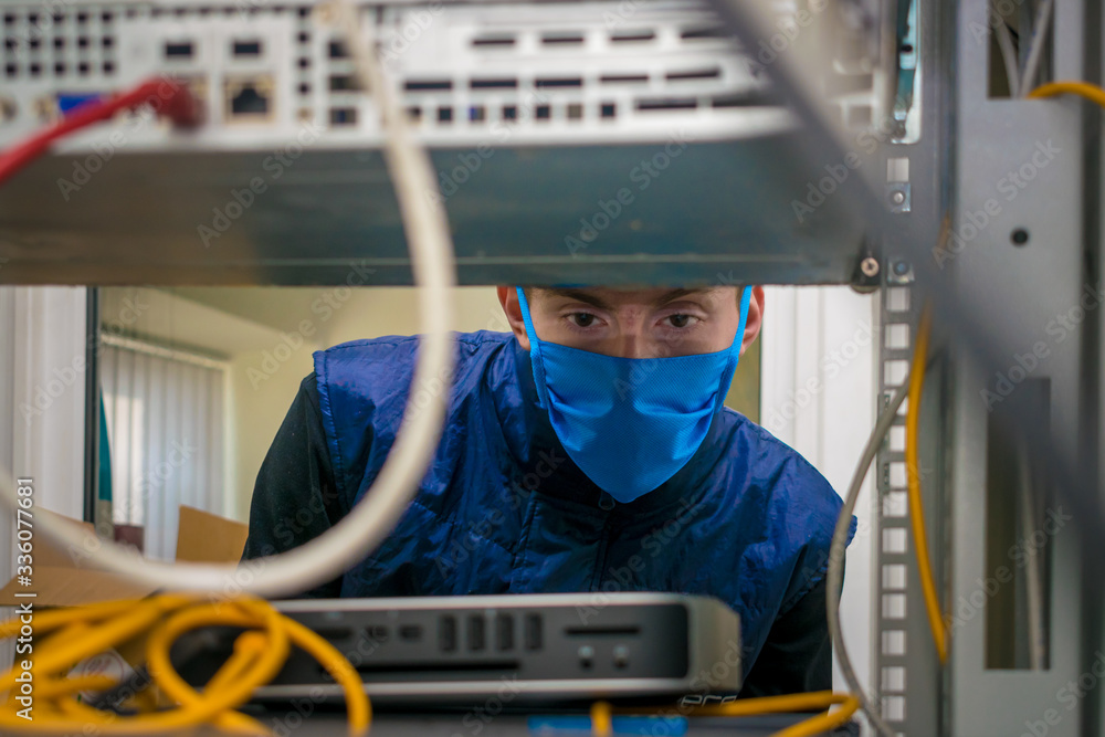 Portrait of a teenager in a data center. A technician in a medical mask ...