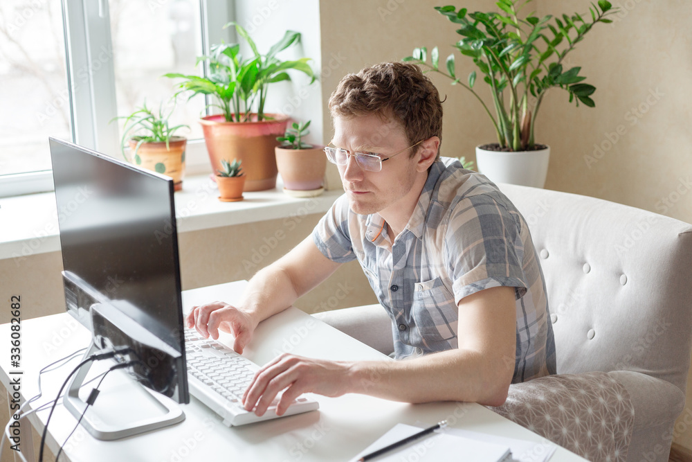 Programmer working from home, remote, home office. A man with glasses ...
