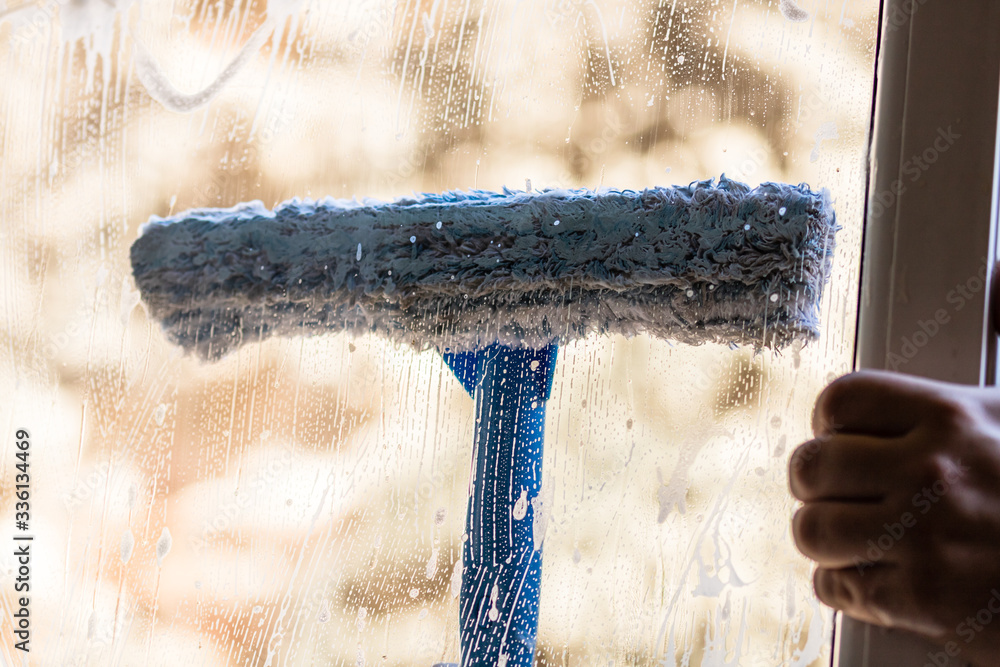 Man cleaning window using window cleaning squeegee and cleaning sprayer ...