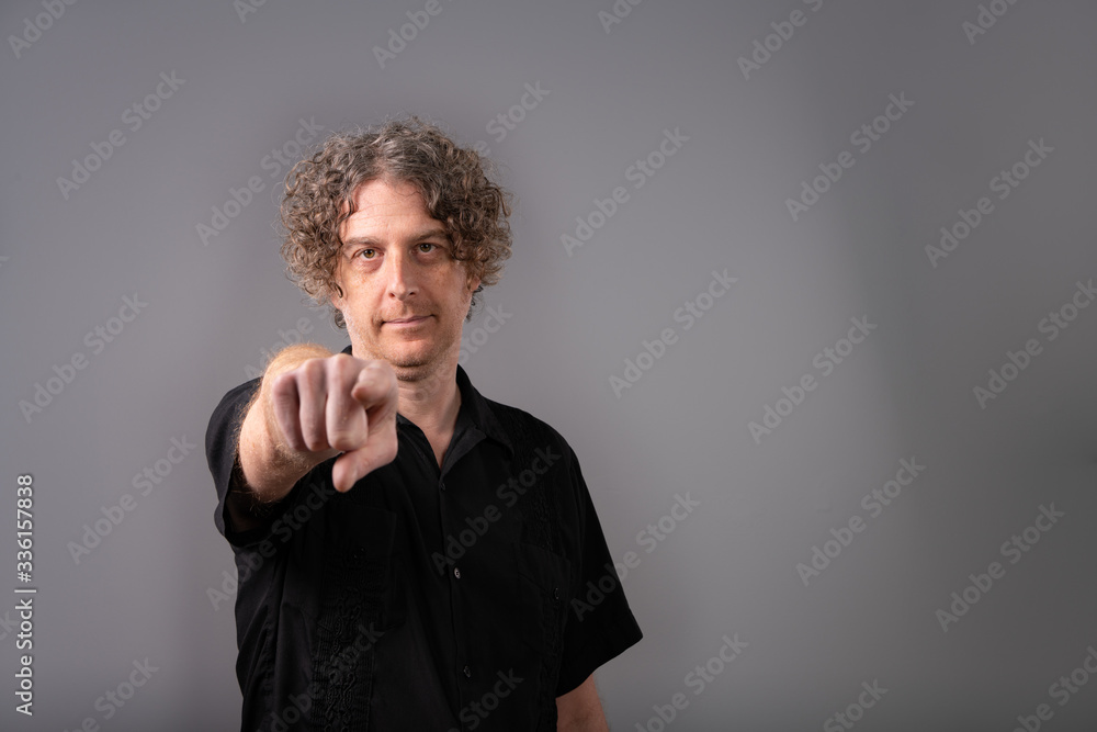 Studio portrait of a man pointing at the camera. The model's face is in ...