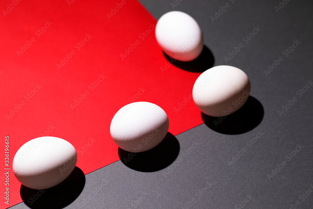 White eggs lie on the border of red and gray background. Red color ...