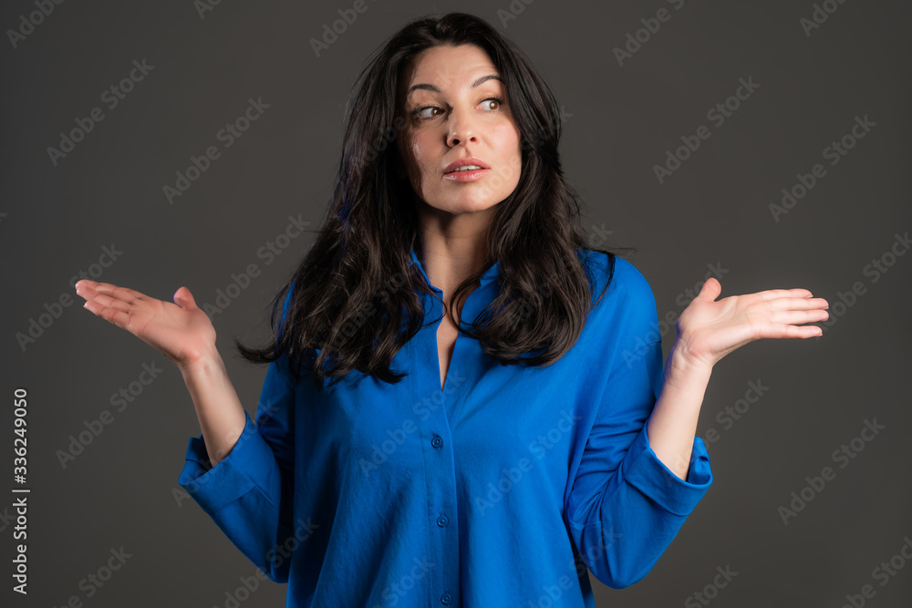 Mature unsure woman shrugs her arms, makes gesture of I don't know ...