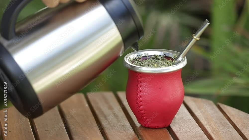 Man making yerba mate tea. Close up pouring hot water into traditional ...