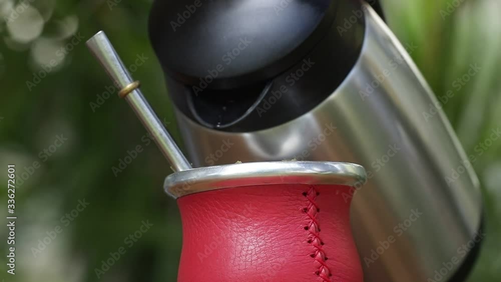 Man making yerba mate tea. Close up pouring hot water into traditional ...