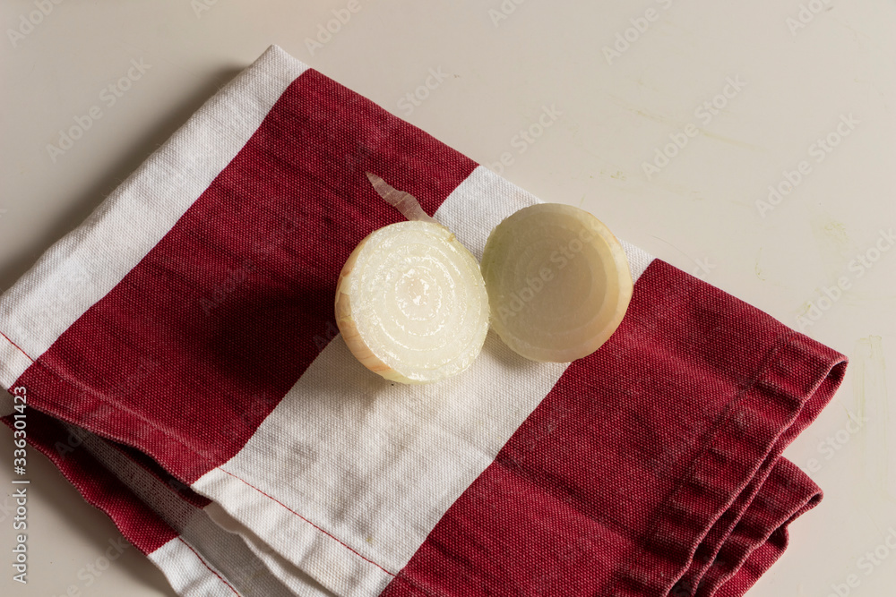 Cebolla blanca partida a la mitad sobre un trapo de rayas rojas y ...