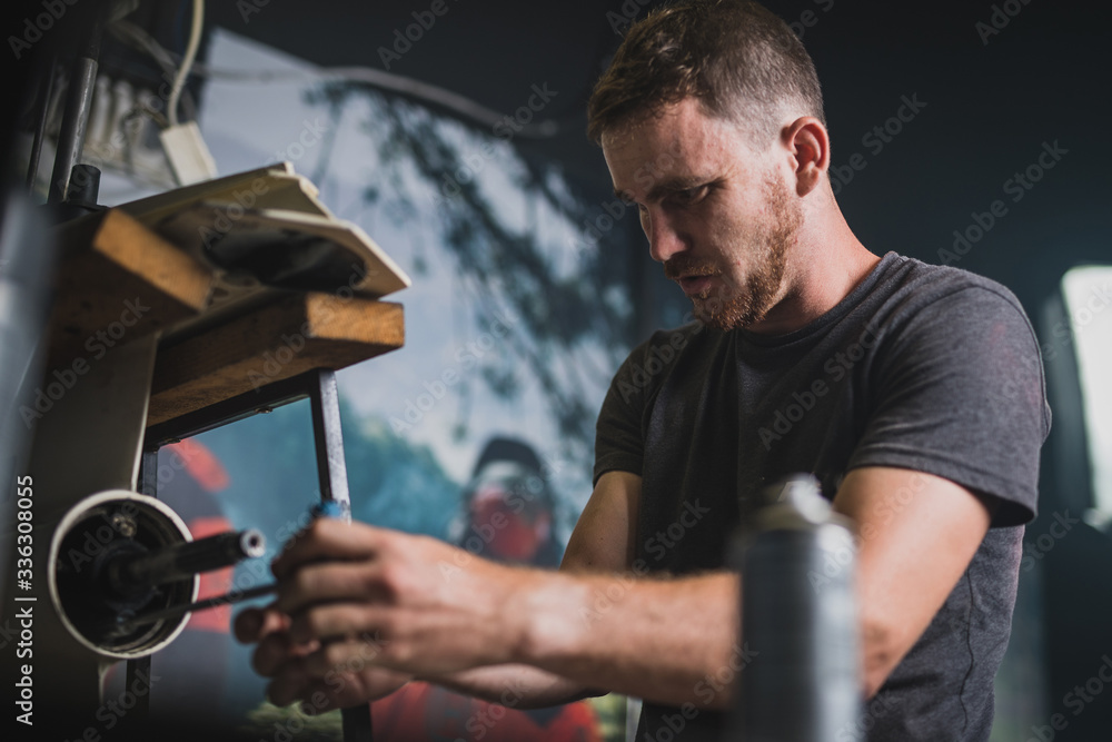 Professional serviceman is repairing an outboard engine using a spanner ...