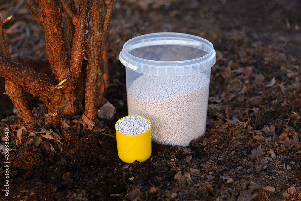 The plastic bucket and the yellow measuring cup with the granulated ...