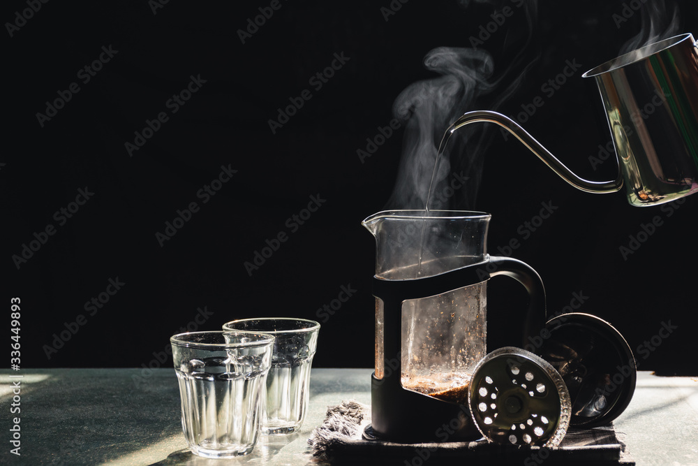 The steam from a pot to a French press coffee maker on the old wood ...