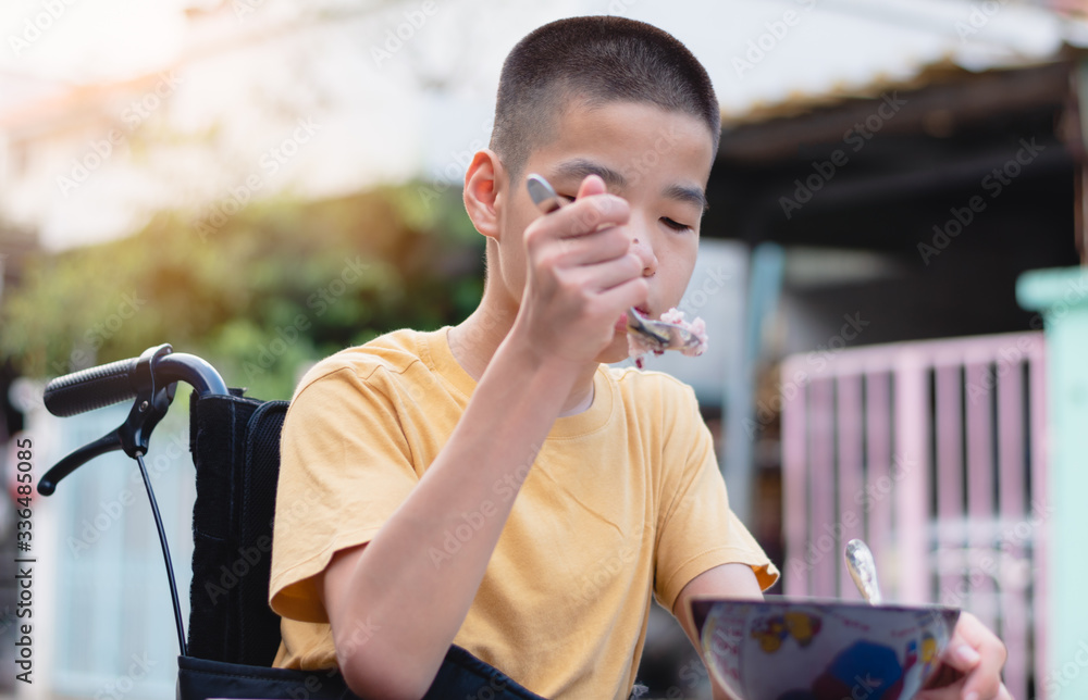 Asian disabled child on wheelchair using a spoon to scoop food by ...