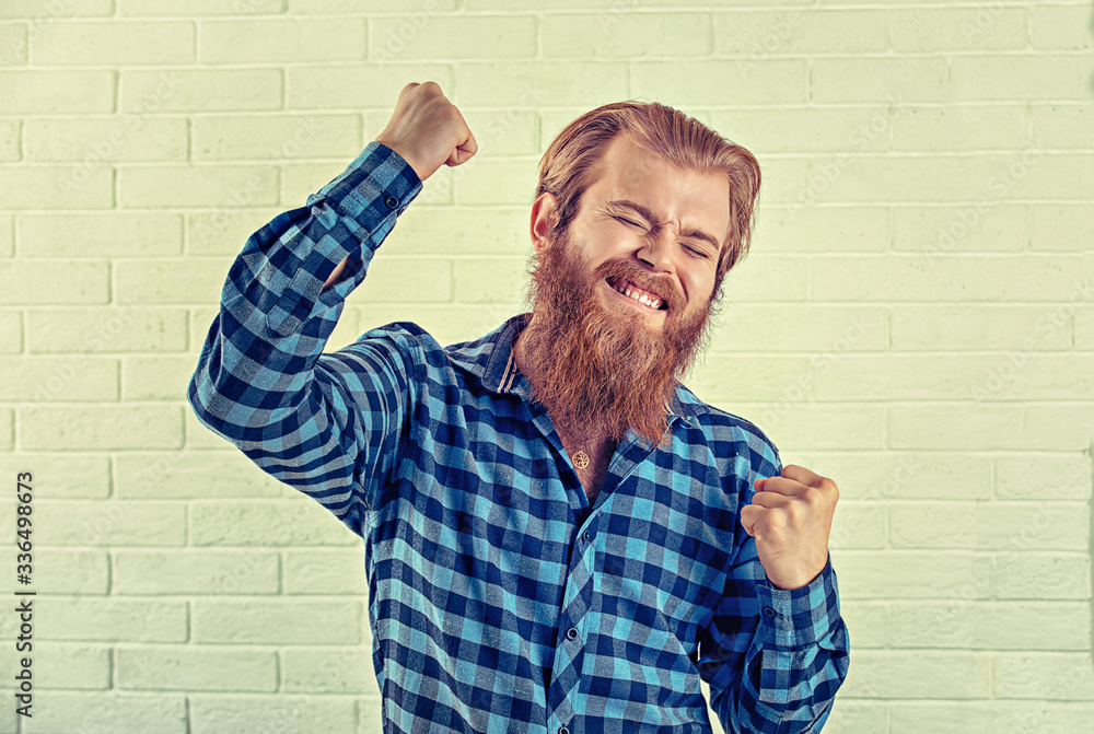 Happy winner. Portrait of a bearded guy celebrating fists up casual ...