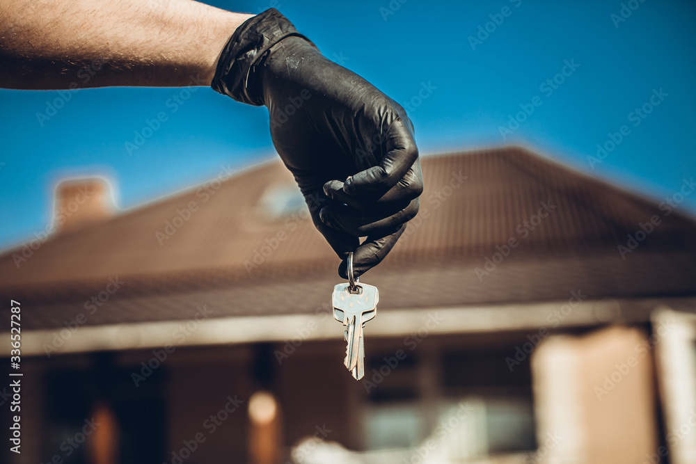 Keys in hand in black glove. Use alcohol spray to corona virus and kill ...