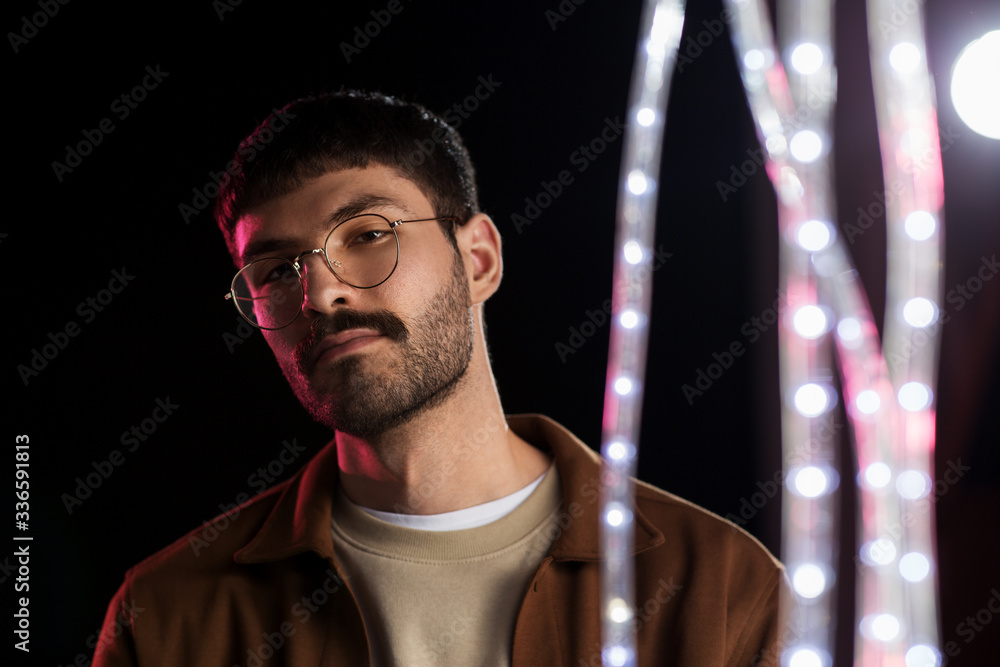 leisure, clubbing and nightlife concept - young man in glasses ain dark ...