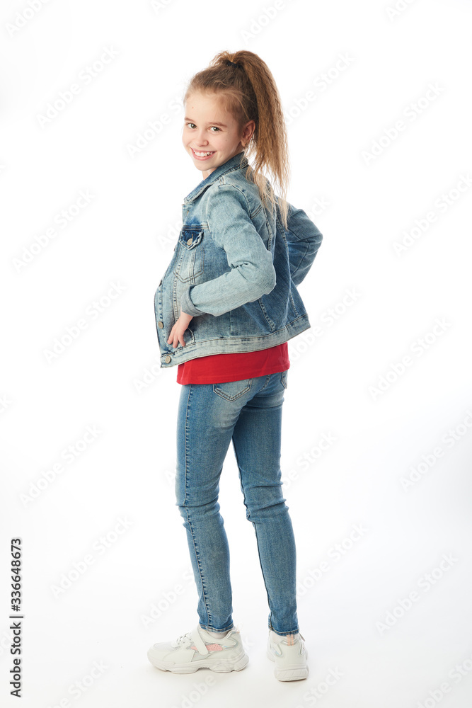 Young girl wearing denim jacket, red shirt, jeans and white sneakers ...