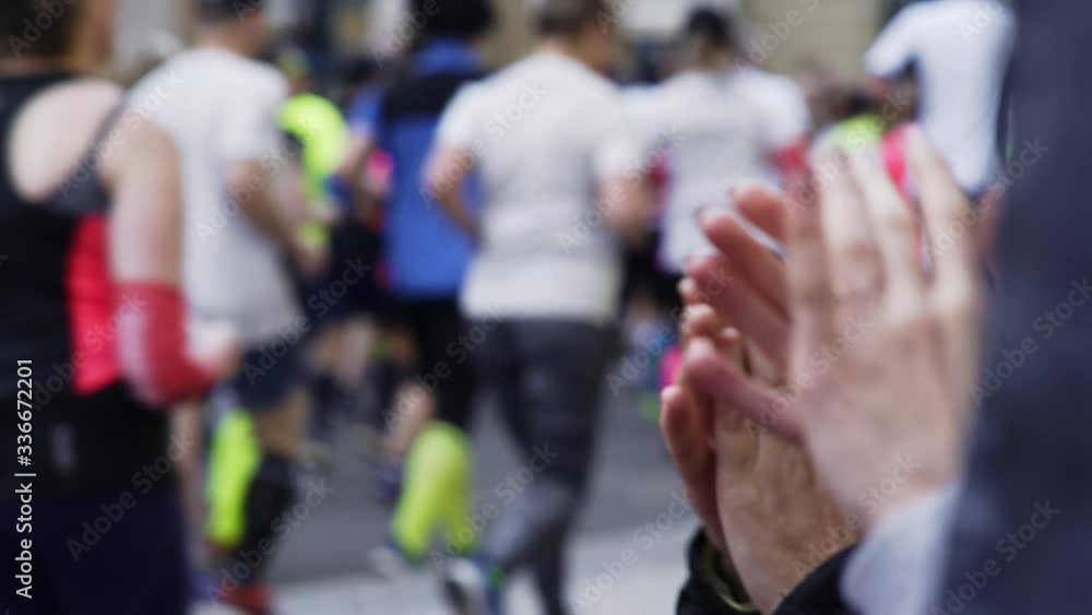 Spectators encourage half marathon runners. Close-up clapping hands ...