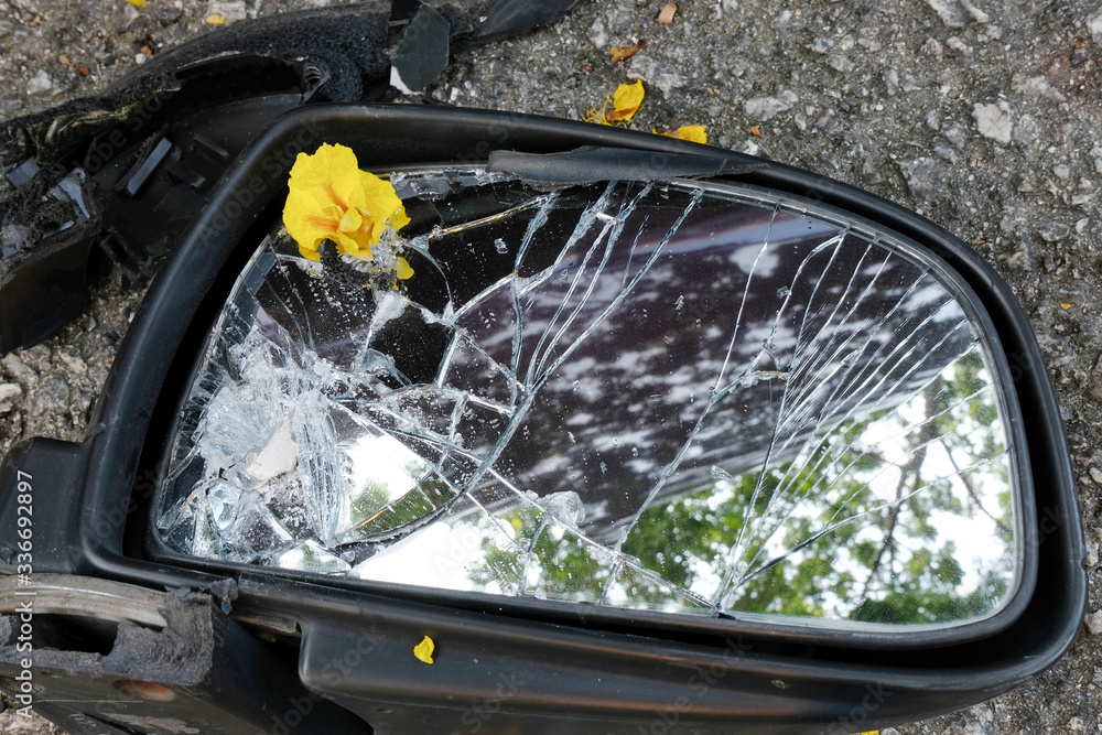 Cracked and shattered glass of a car side view mirror lying on a street ...