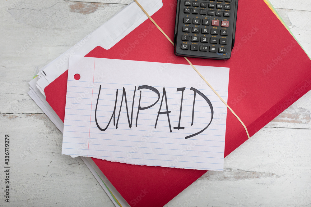 Foto de Unpaid, sign laying on a stack of late payments and bills on a ...