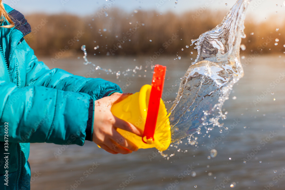 Child playing with water. Kid pours out water from yellow plastic ...