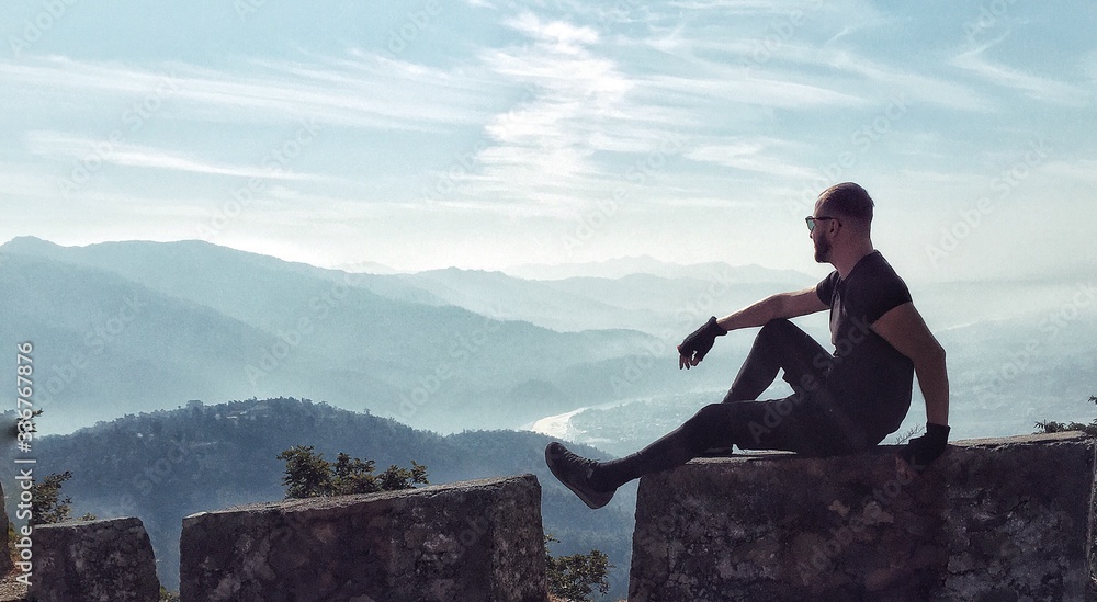 Full Length Of Man Looking At Mountains While Relaxing On Retaining ...