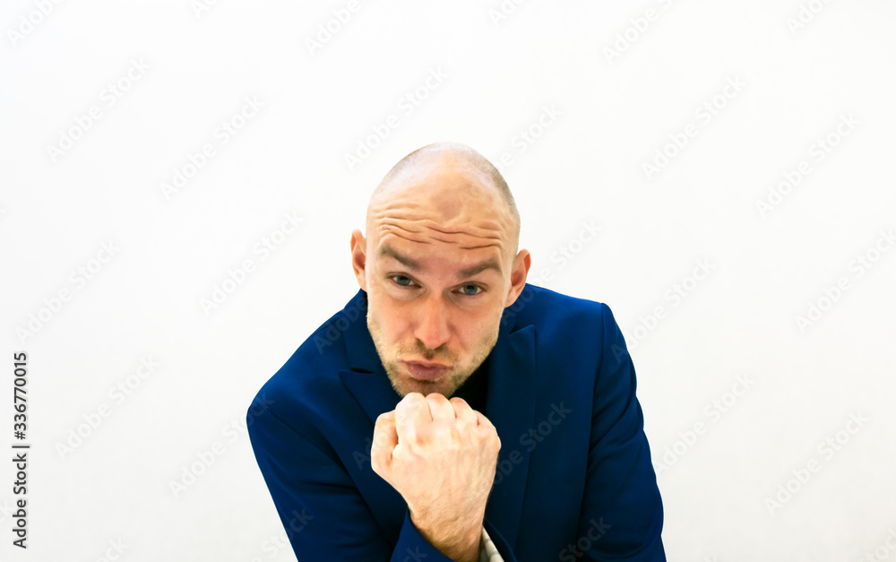 bald business boss in blue suit is showing big fist and expresses ...
