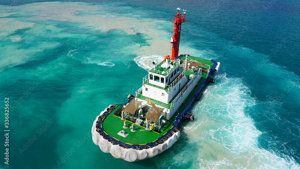 Colored tugboat works in port. bright tugboat in blue water. industrial ...