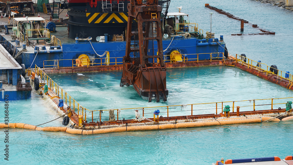 Huge excavator on floating platform in the blue water of the Pacific ...