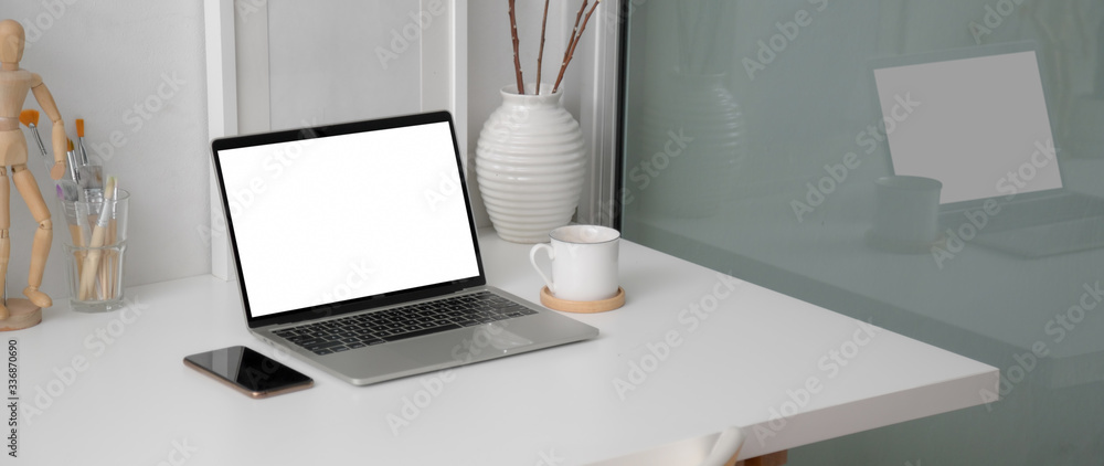 Cropped shot of simple office desk with blank screen laptop, smartphone ...