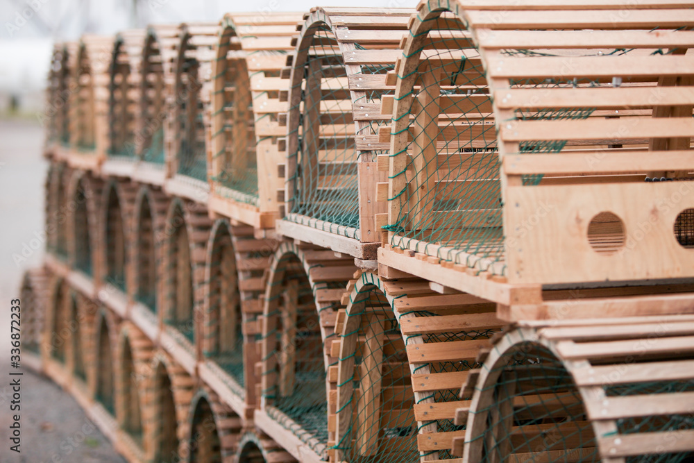 Stack of rounded wooden lobster cages with green nets. Stock Photo ...