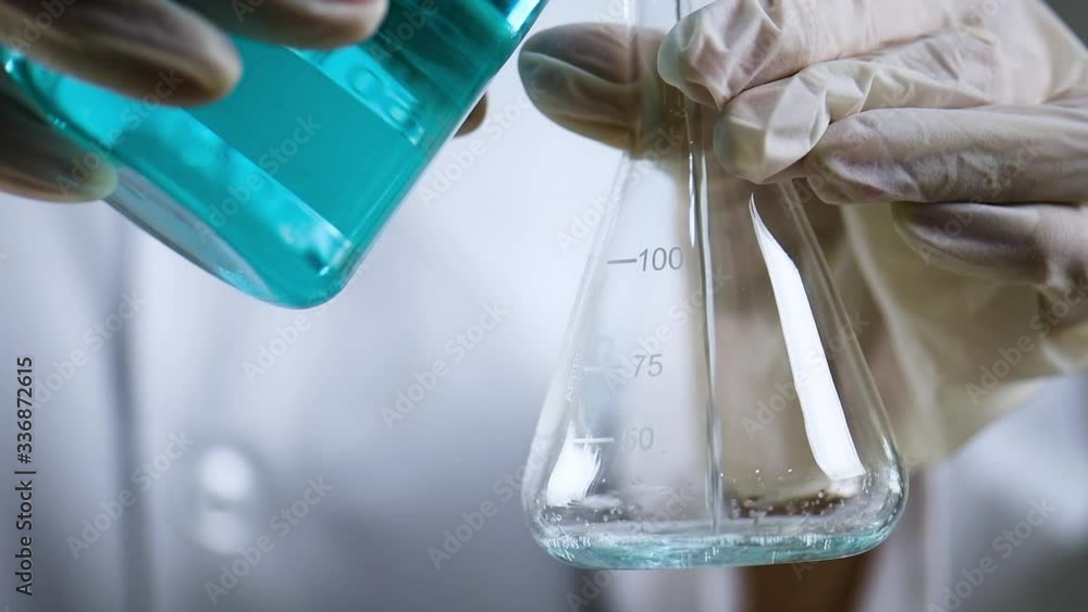 scientist hand holding a medical dropper filled with blue solution ...